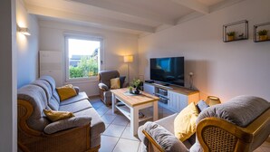 Uma sala de estar moderna com um sofá, poltronas, uma mesa de centro e uma televisão.