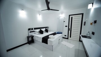 Quarto de hotel moderno com cama, mesa de cabeceira e ventoinha no teto.