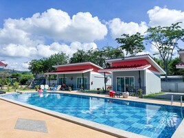 Piscina com dois edifícios próximos, um com telhado vermelho e outro com telhado branco.