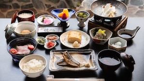 Diversos pratos e utensílios japoneses em uma mesa, incluindo arroz, peixe e vegetais em conserva.