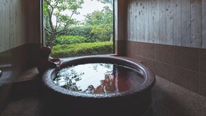 Banheira de hidromassagem com vista para uma árvore e vegetação lá fora.