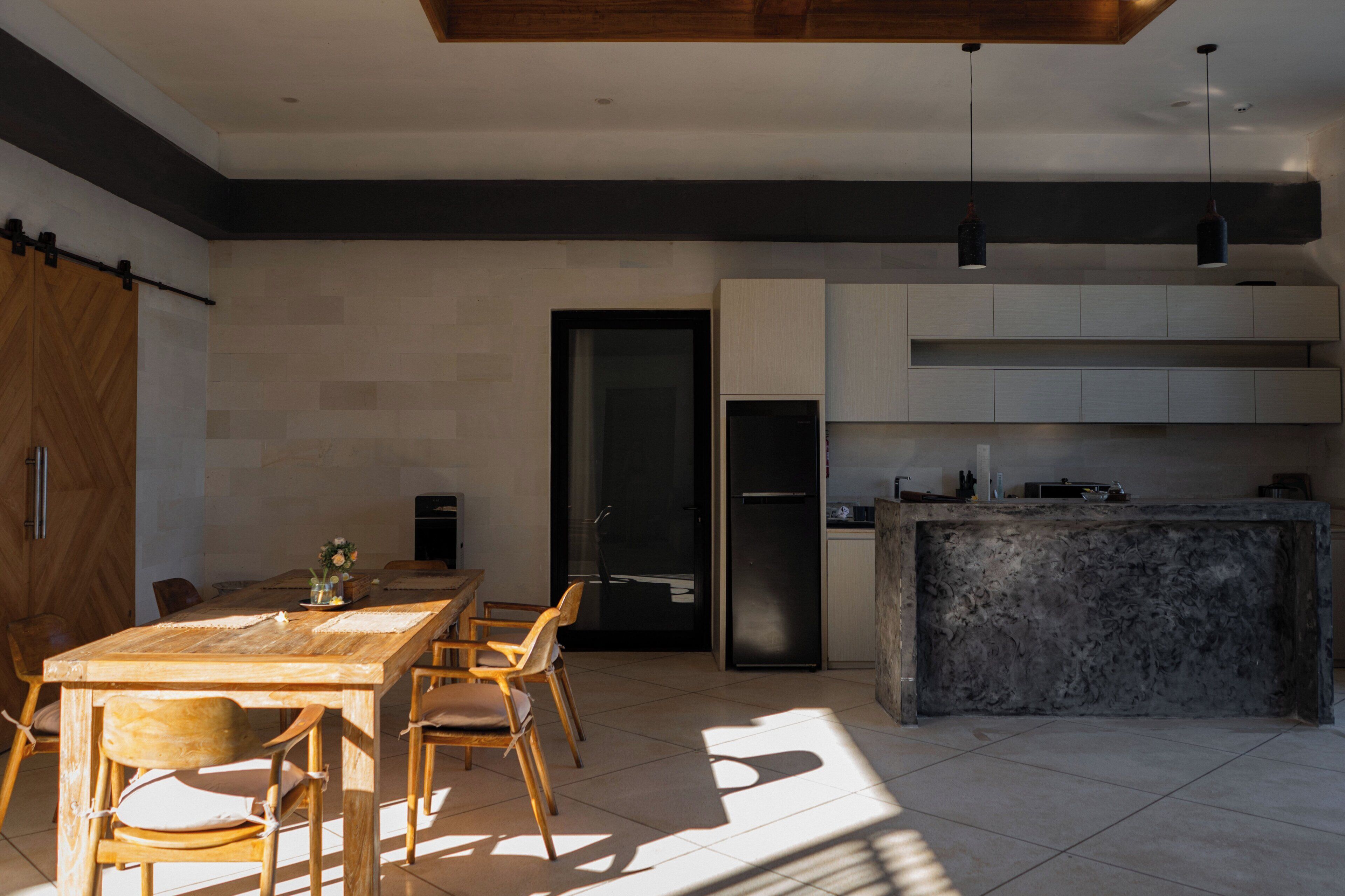 Uma cozinha moderna com bancada de mármore, mesa de jantar de madeira e cadeiras.