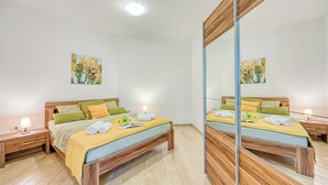 Quarto com cama de madeira, mesa de cabeceira, espelho e quadro pendurado na parede.