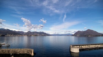 Um lago calmo com montanhas ao fundo, um cais e um farol.