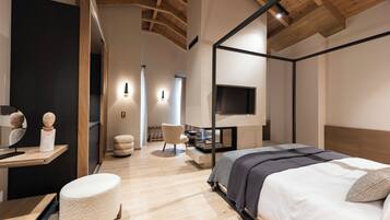 Quarto moderno com uma cama, televisão, escrivaninha e cadeira.