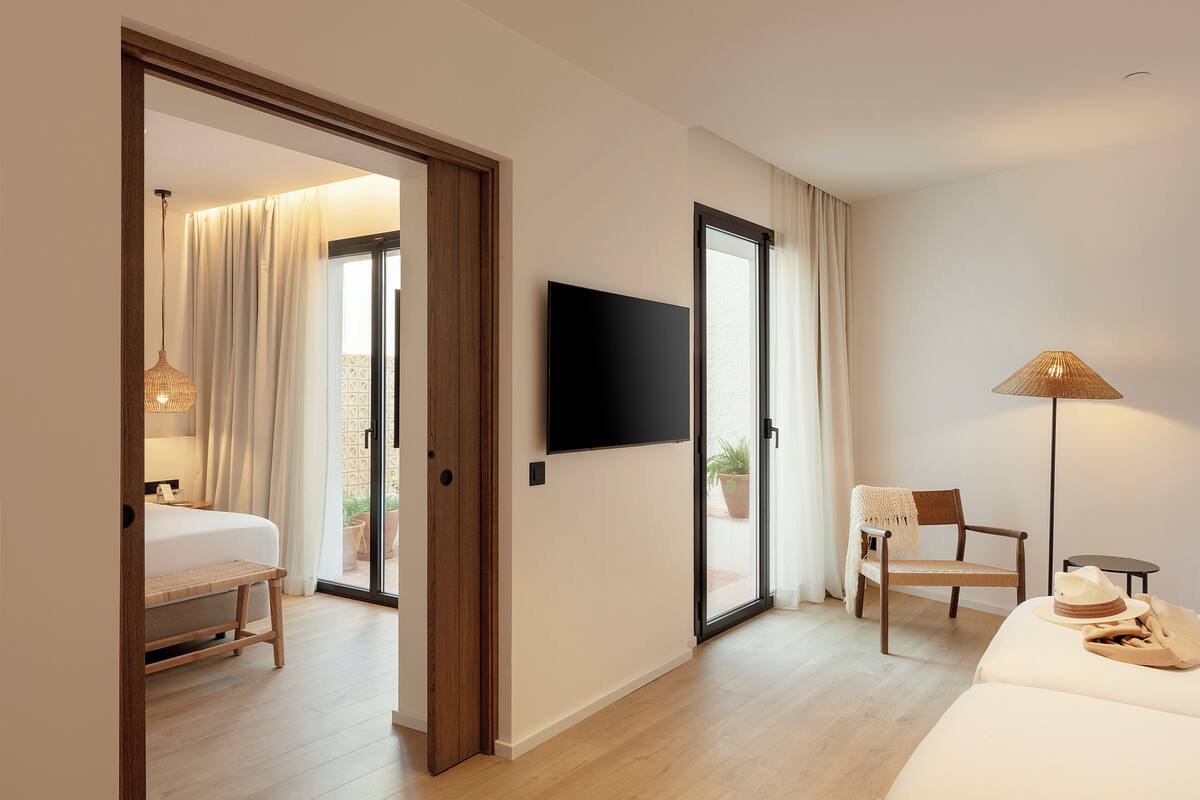 Quarto de hotel com cama, televisão, cadeira e abajur.