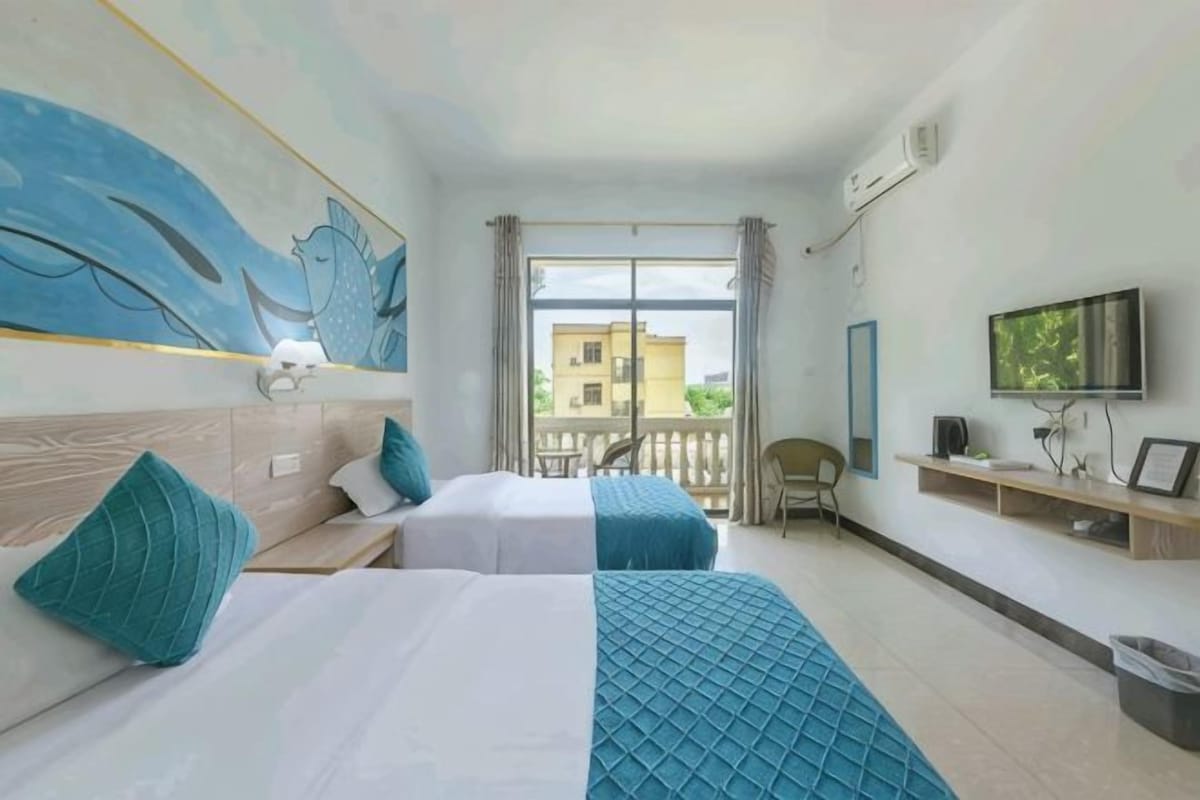 Quarto de hotel com duas camas, televisão, varanda e vista do edifício.