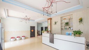 Uma área de recepção de hotel com balcão, espaço de espera com três assentos circulares e escada que leva a outro andar.