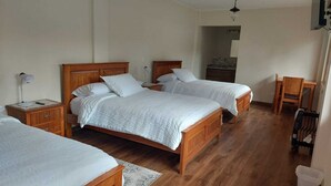 Quarto de hotel com duas camas de madeira, uma secretária pequena, uma cadeira e um radiador.
