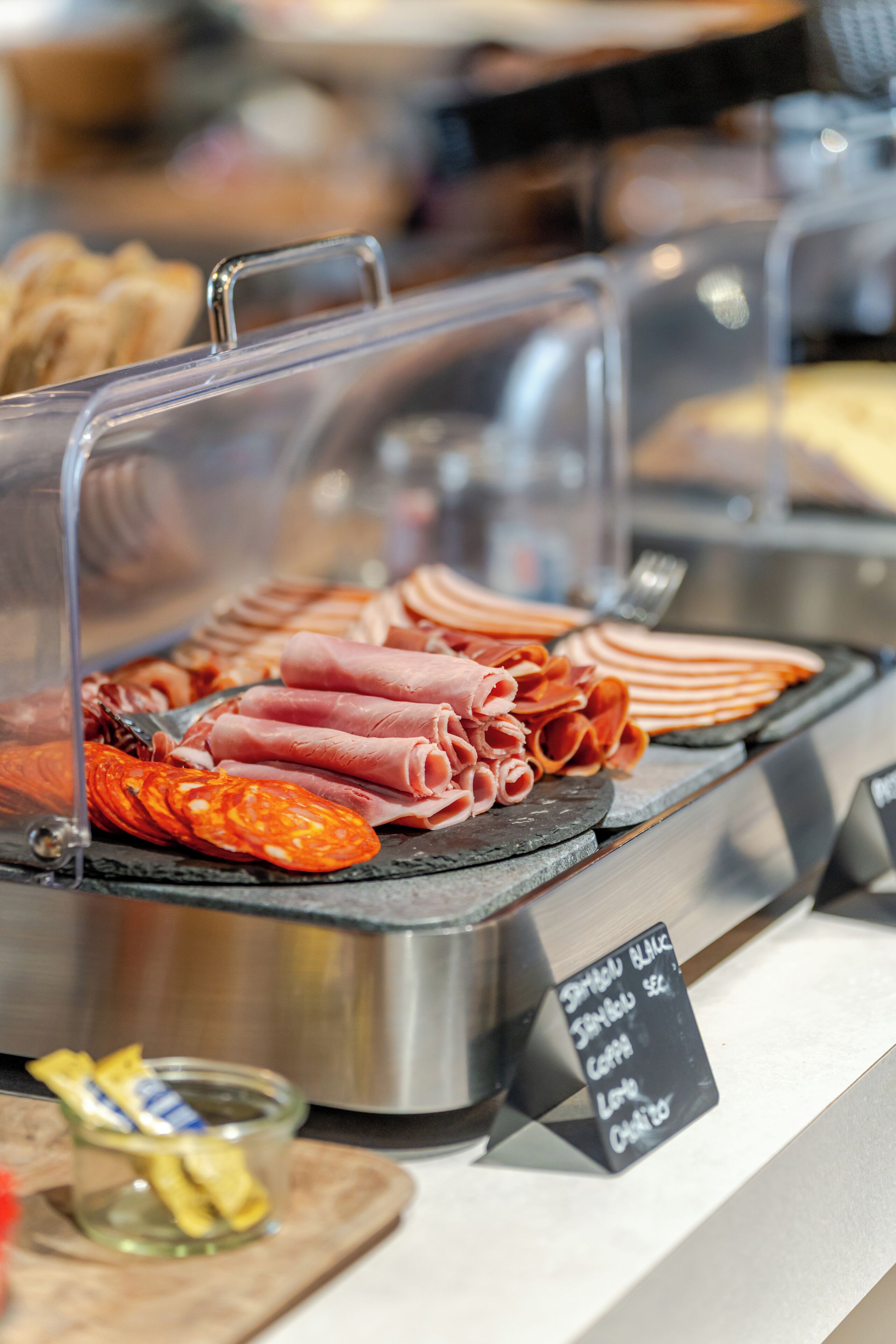 Balcão de fiascos com diversos tipos de carne e queijos expostos em recipientes de plástico transparente.