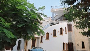 Um edifício com fachada branca, várias janelas e uma escadaria que leva a um andar superior.