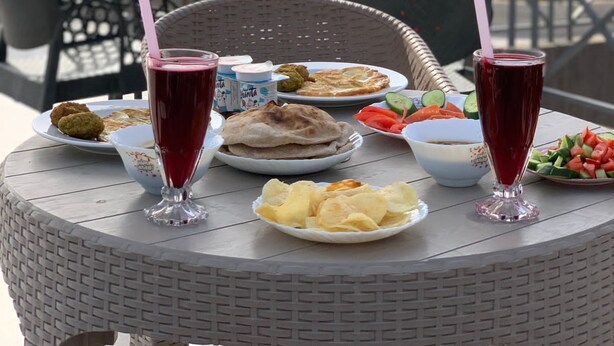 Mesa com comida e bebidas em varanda com vista para uma pirâmide.