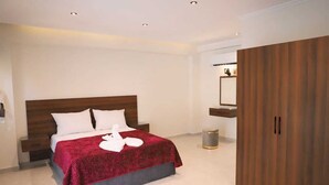 Quarto de hotel moderno com uma cama grande, cabeceira de madeira e um guarda-roupa.