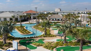 Um campo de golfe com putting green, uma piscina pequena e palmeiras.