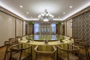 Sala de conferência com mesa redonda, cadeiras e um candelabro.
