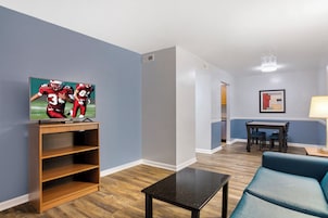 Sala de estar com televisão, mesa de centro, sofá e área de jantar com mesa e cadeiras.