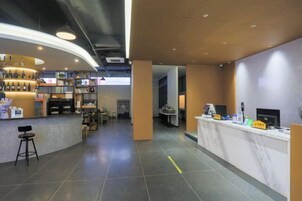 Um saguão de hotel com balcão de recepção, área de estar e bar.