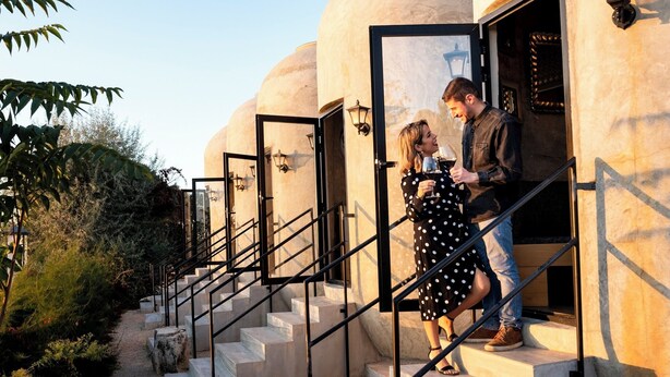 Um casal saindo de um edifício com uma escadaria que leva a um terraço.