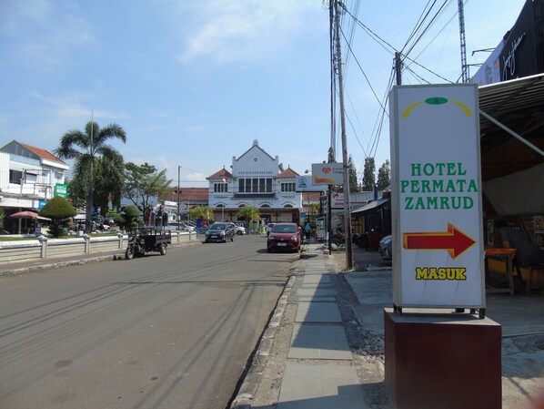 Vista da rua com uma placa do Hotel Permata Zamrud, indicando o caminho para Masuk.