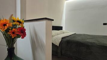 Quarto de hotel com cama, mesa de cabeceira e um vaso com flores.