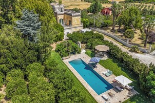 Vista aérea de uma propriedade com piscina, área de estar ao ar livre e vegetação exuberante.