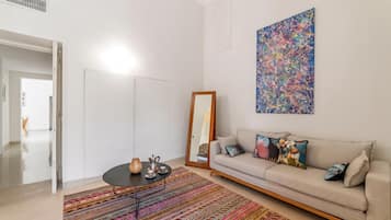 Uma sala de estar com sofá, mesa de centro e um quadro abstrato colorido.