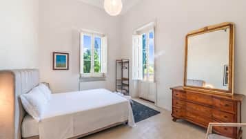 Quarto com cama, penteadeira, espelho e janela.