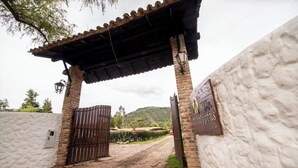 Uma entrada rústica com um arco de tijolos, um portão de metal e uma placa com a inscrição 'Villa Erythros'.