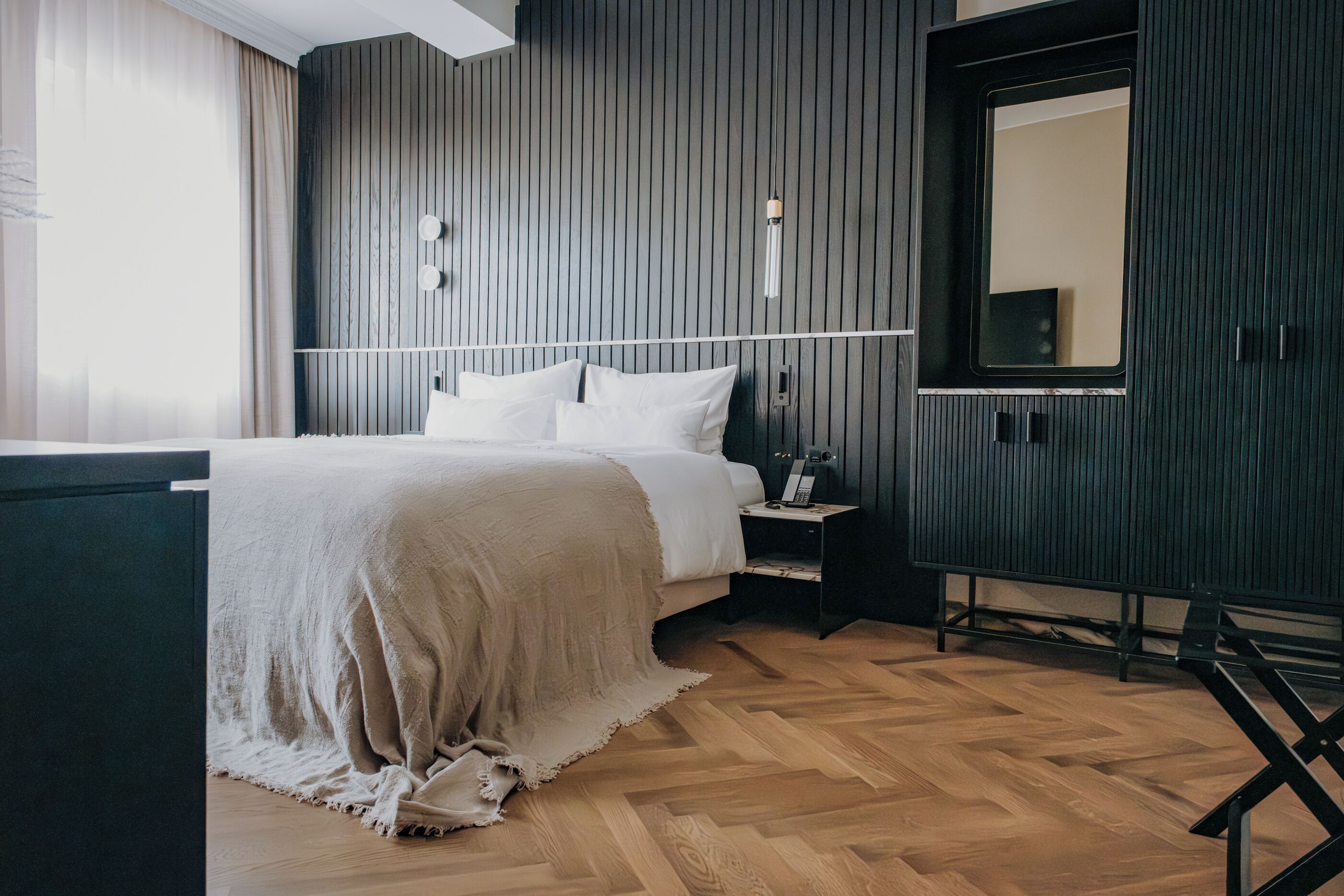Quarto moderno com cama, mesa de cabeceira e um espelho grande.