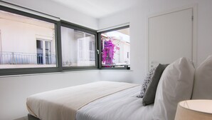 Um quarto com uma cama, uma janela e uma porta.