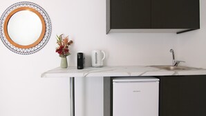 Uma cozinha com bancada branca, pia, cafeteira e máquina de lavar louça.