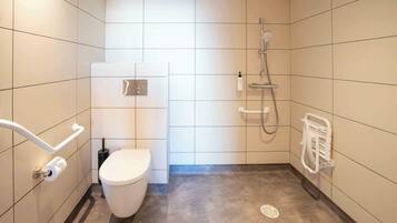 Uma casa de banho moderna com sanita, chuveiro e secador de mãos.