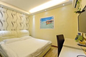 Quarto de hotel com uma cama, uma escrivaninha e uma cadeira. Há um quadro na parede e uma televisão na escrivaninha.