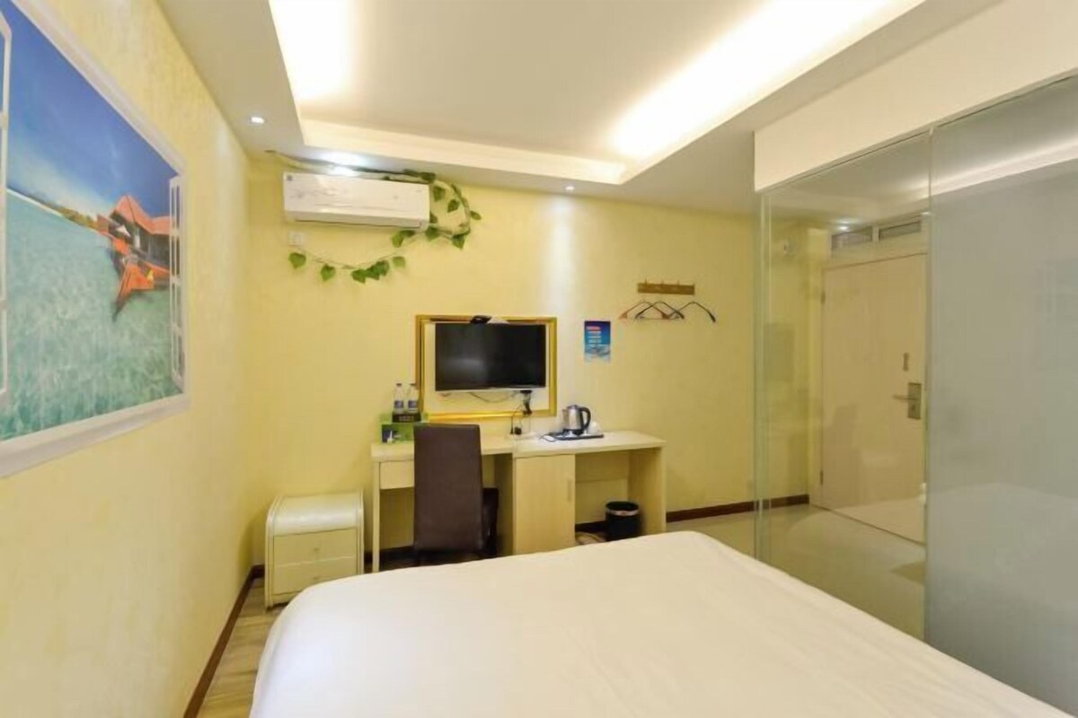 Quarto de hotel com cama, escrivaninha e televisão.