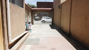 Um beco estreito com portão, calçada de azulejos e um carro estacionado.