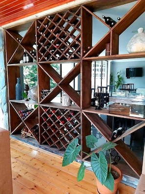 Uma adega com garrafas de vinho, uma televisão e uma área de refeições com cadeiras e uma mesa.