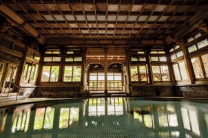 Piscina interna com chão de azulejos e vigas de madeira no teto.