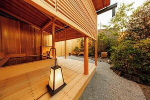 Um deck de madeira com hidromassagem, um candeeiro e um jardim.