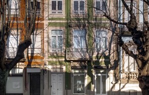 Um edifício de vários andares com fachada verde, várias janelas e varandas.