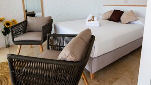 Quarto com cama, duas cadeiras de vime, espelho e luminária suspensa.