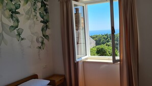 Quarto com cama, uma mesinha e janela com cortinas.