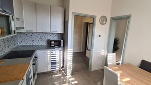 Cozinha moderna com armários brancos, micro-ondas e área de jantar com mesa e cadeiras de madeira.