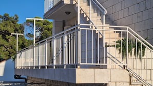 Escadaria com guarda-corpos brancos que leva à entrada de um edifício.