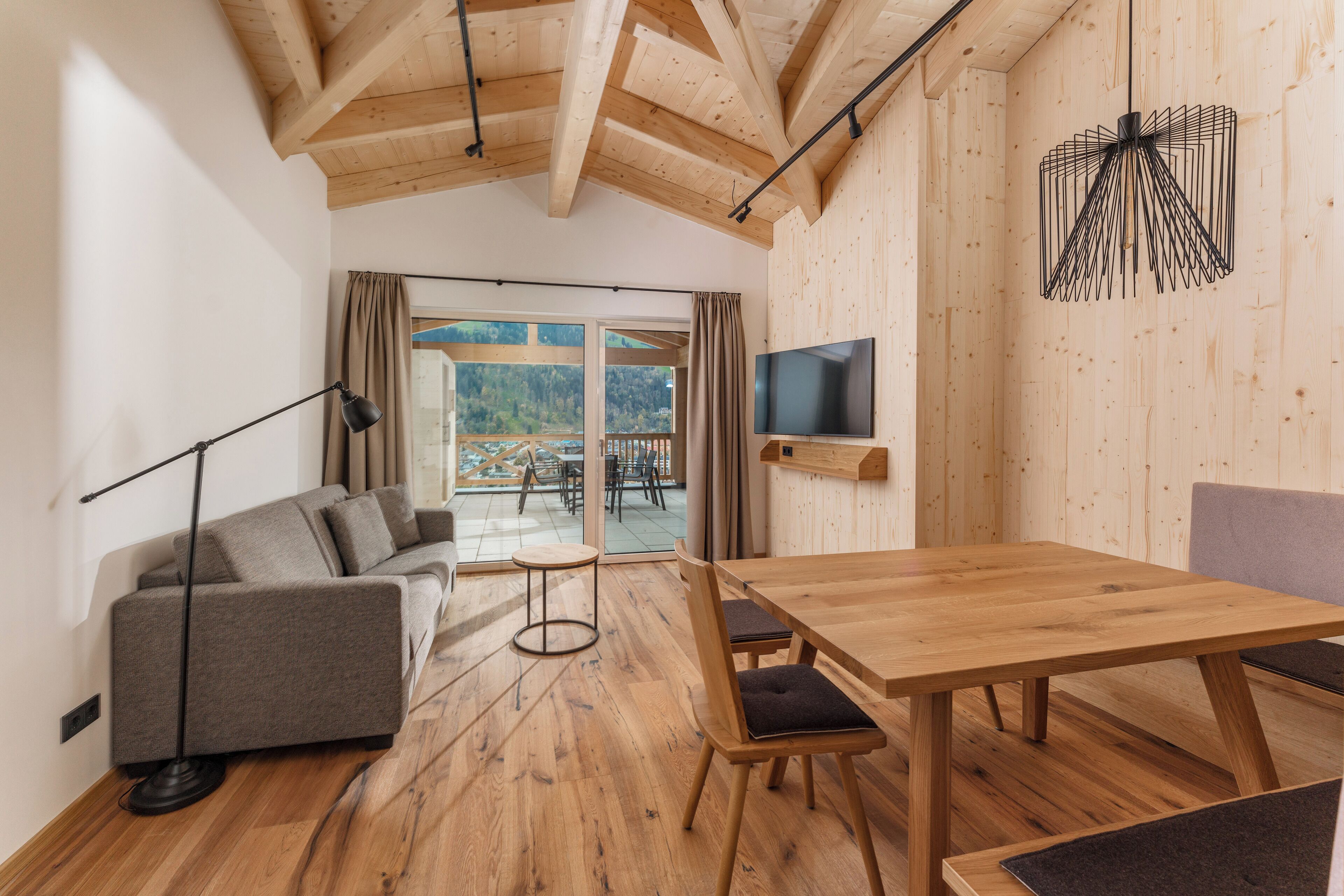 Uma sala de estar moderna com teto de madeira, um sofá, uma TV e uma mesa de jantar.
