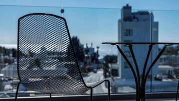 Cadeira e mesa de metal numa varanda com vista para a cidade.