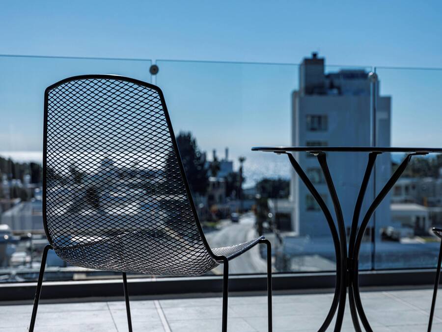 Cadeira e mesa de metal numa varanda com vista para a cidade.