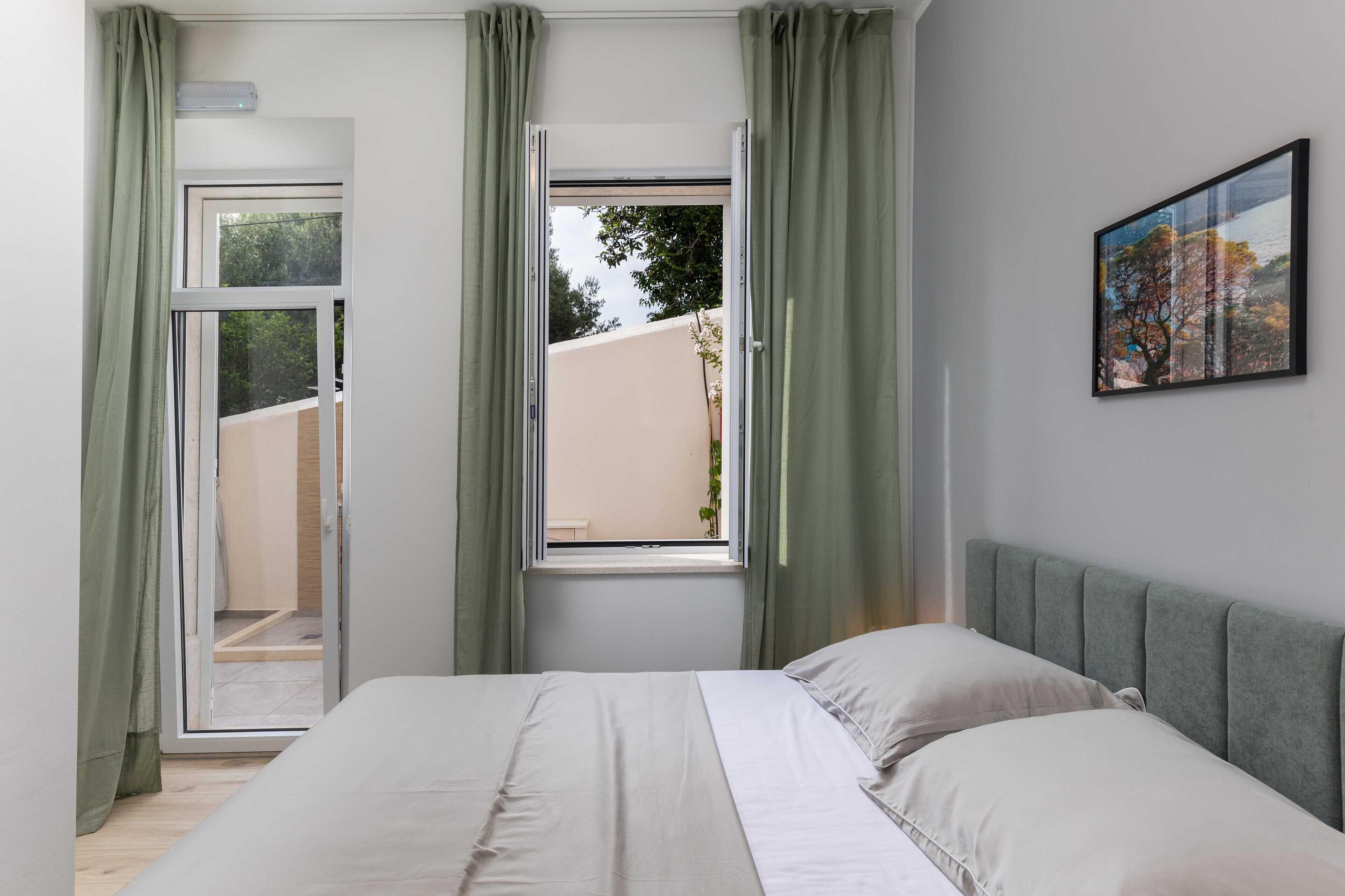 Quarto com cama, janela e um quadro na parede.