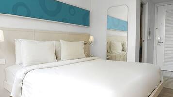 Quarto de hotel com uma cama grande, mesa de cabeceira, espelho e porta.