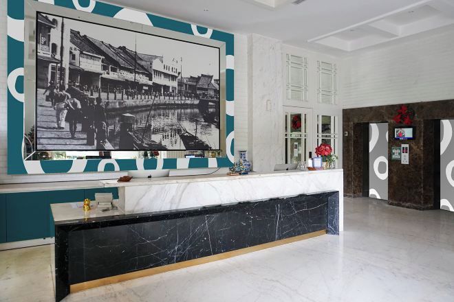 Uma área de recepção com balcão de mármore, uma grande fotografia em preto e branco na parede e um design moderno com detalhes em verde-água e branco.