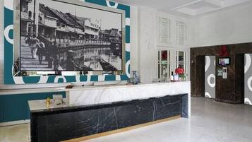 Uma área de recepção com balcão de mármore, uma grande fotografia em preto e branco na parede e um design moderno com detalhes em verde-água e branco.